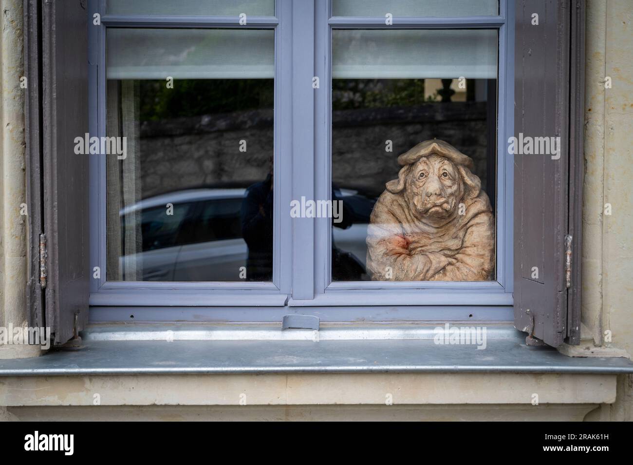 A model of a pig wearing a beret looking out of a window of a house in ...
