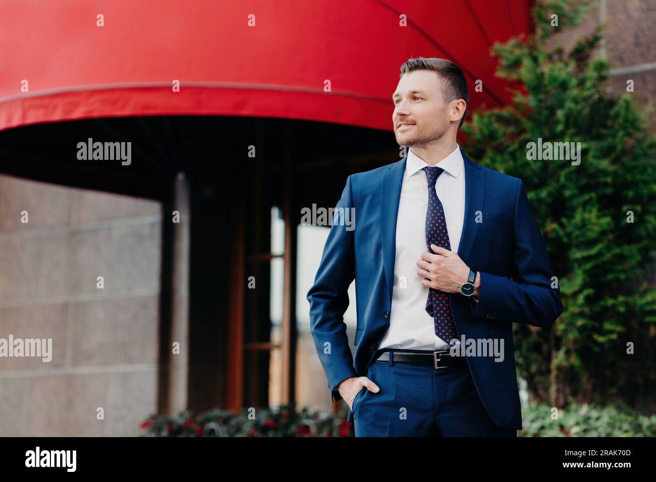 Smart male banker plans work, poses near building, portrays business ...