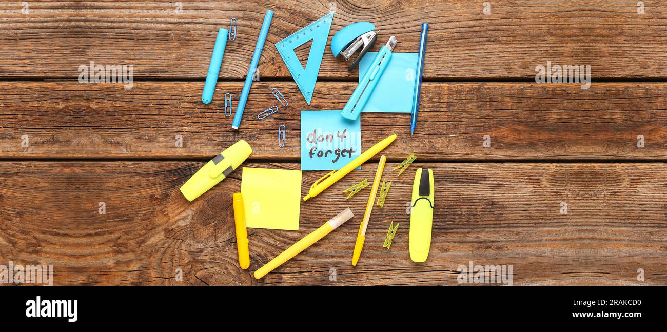 Sticky note with text DON'T FORGET and stationery on wooden background ...