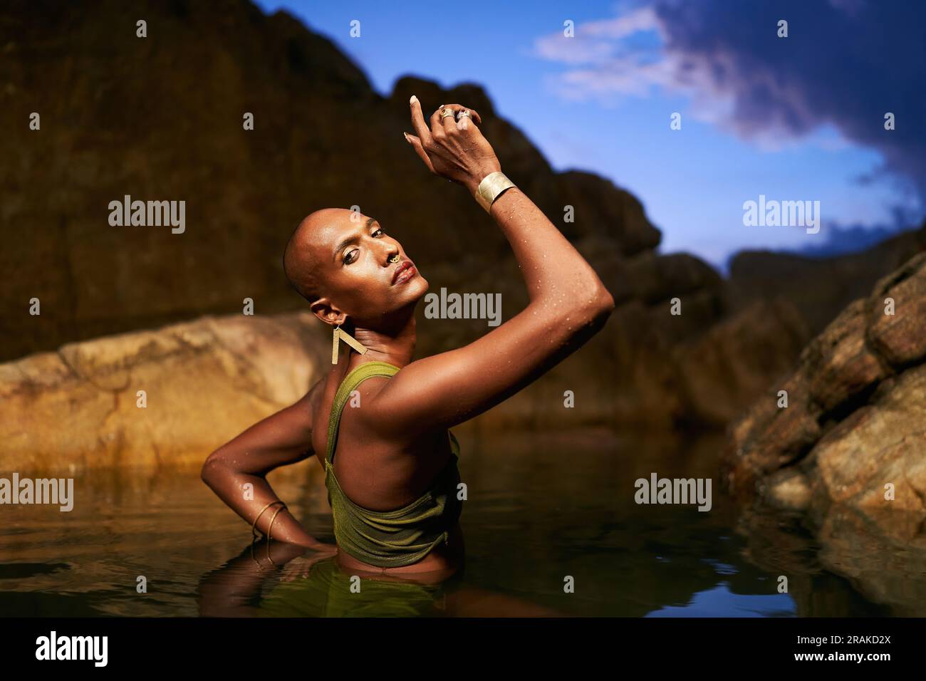 Androgynous bipoc lgbtq model poses in water inside natural pool at ...