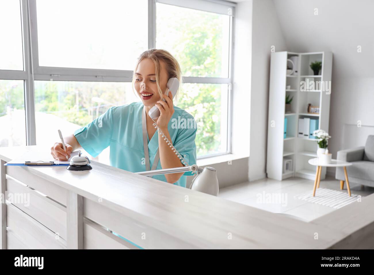 Female medical intern talking by telephone at reception in clinic Stock ...