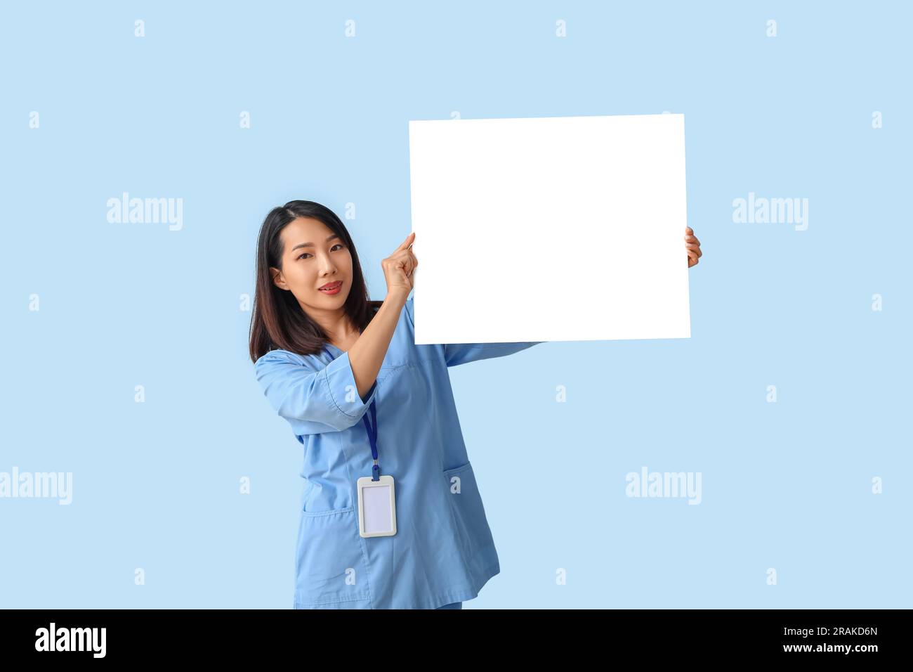 Female Asian medical intern with blank paper sheet on blue background ...