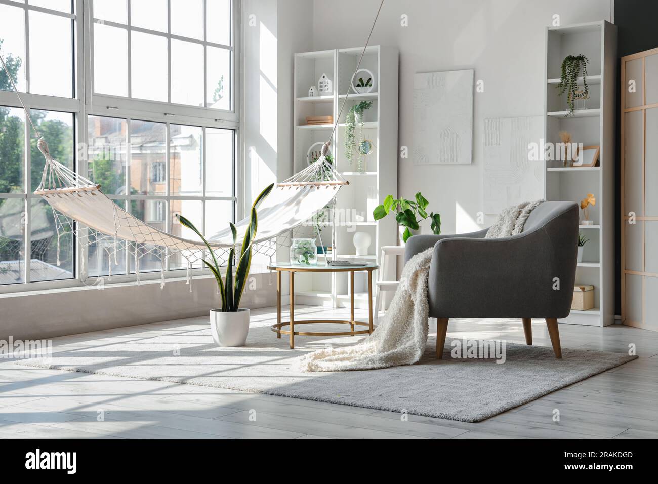 Interior of light living room with hammock, table and armchair Stock ...