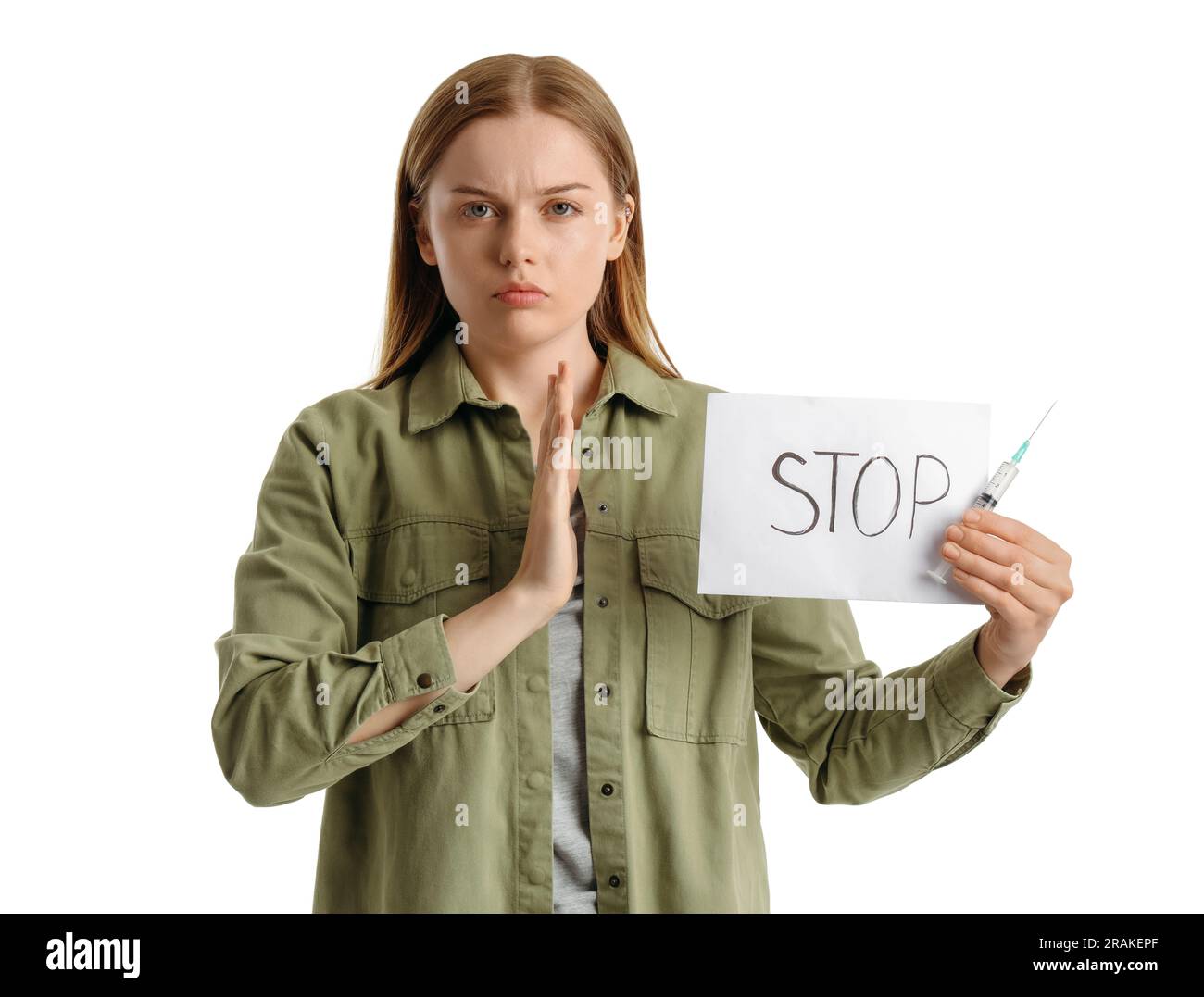 Young female junkie holding syringe and paper with word STOP on white ...
