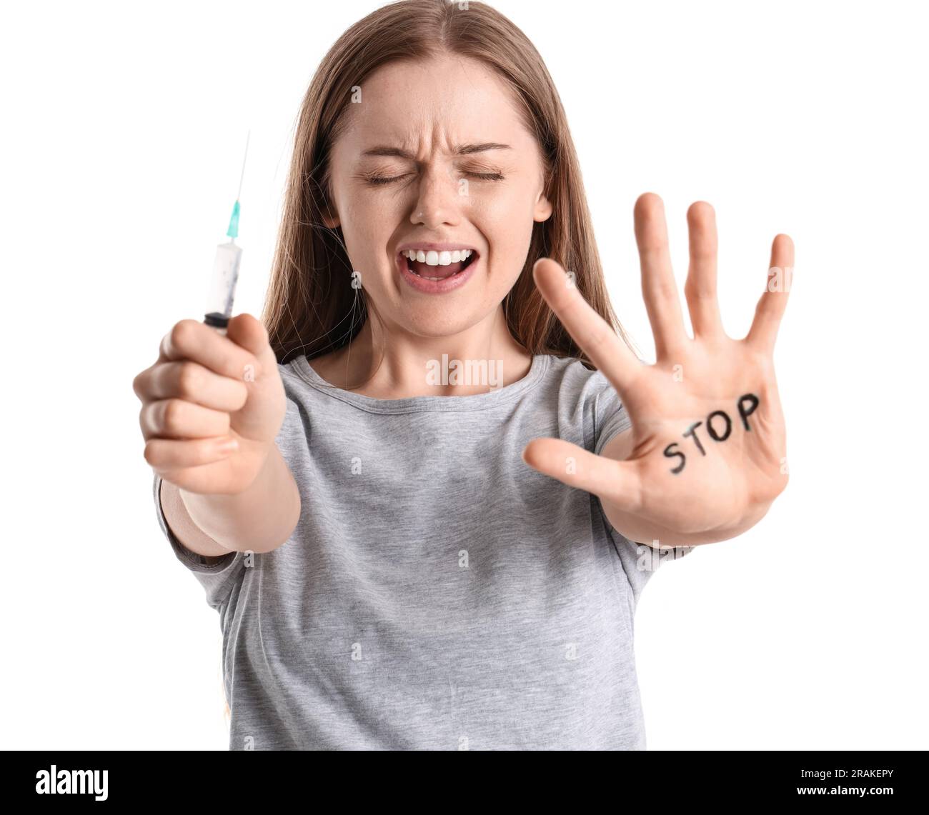 Screaming female junkie with syringe and word STOP written on her palm ...
