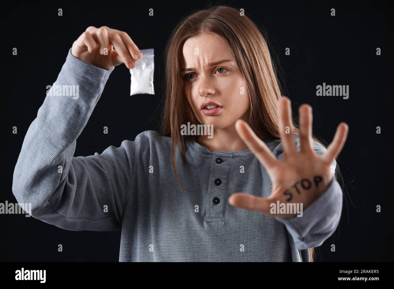 Young female junkie with drugs and word STOP written on her palm ...