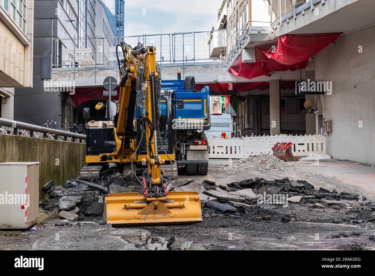 Yellow excavator and truck on a construction site between buildings ...