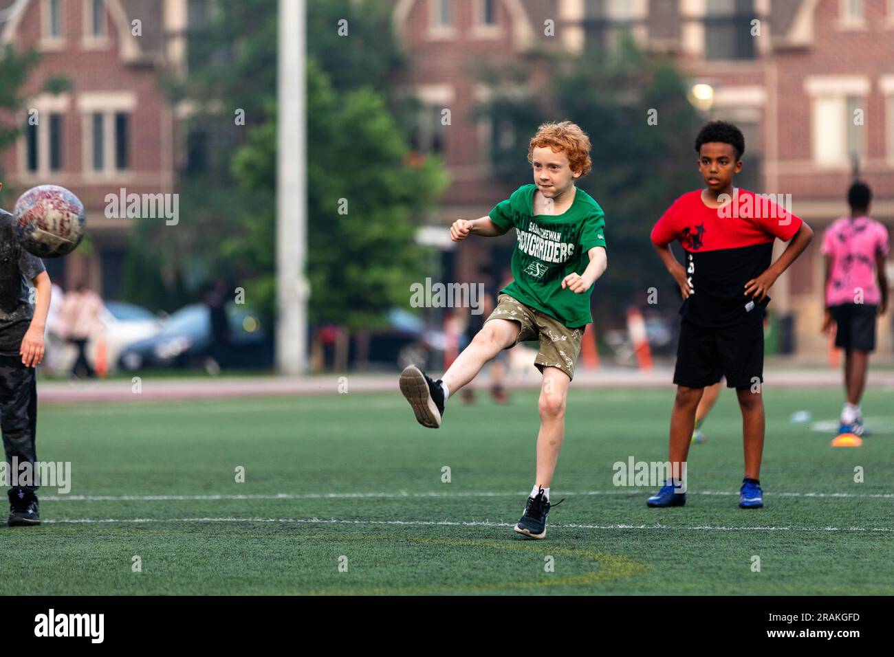 A boy practises a soccer kick during a summer evening on an inner city ...