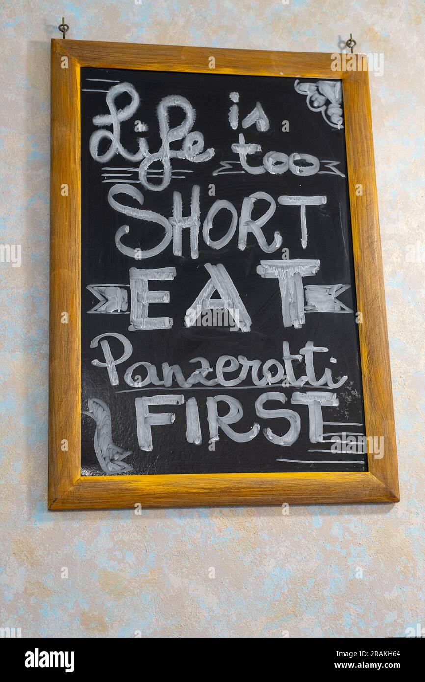 A chalkboard sign with the text 'Life is short, eat panzerotti first ...