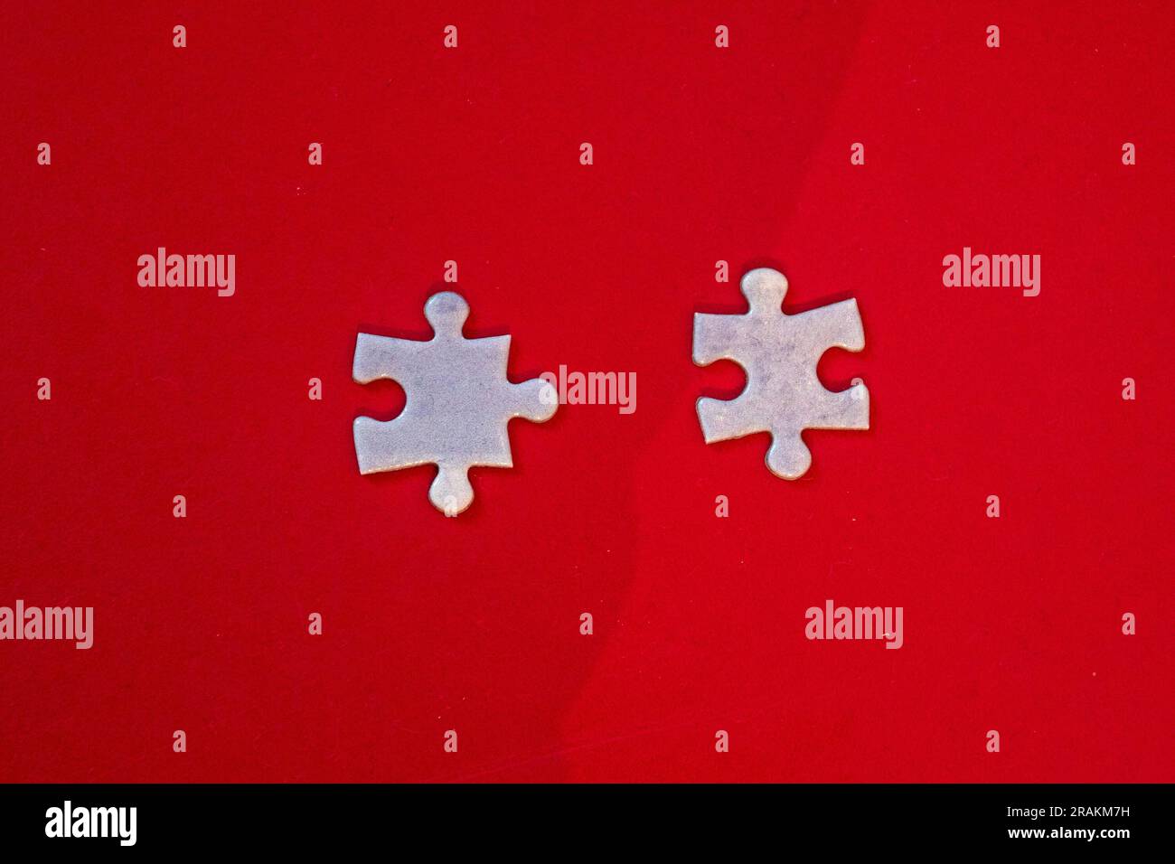 two matching disconnected jigsaw puzzles on a red background. concept ...