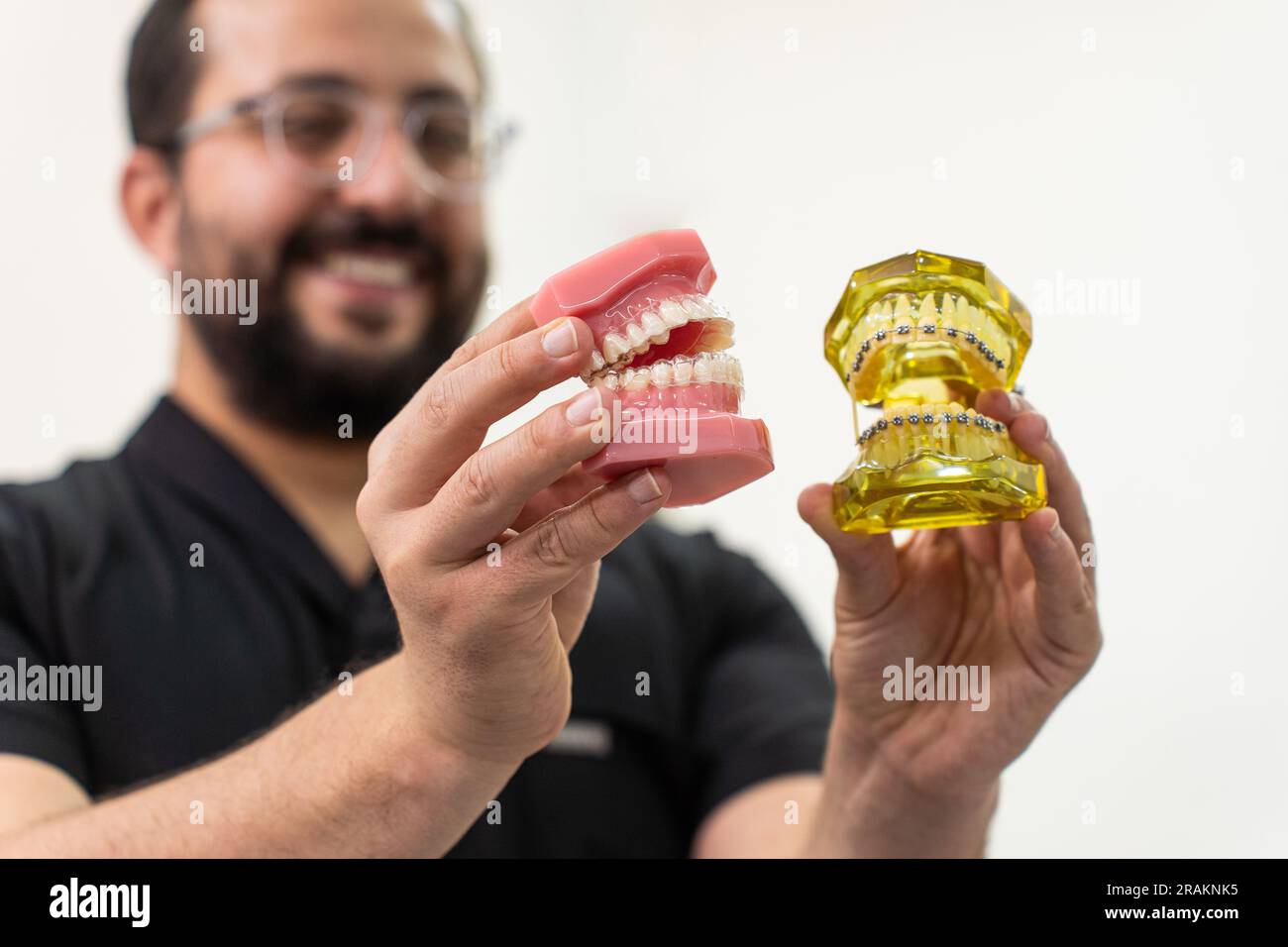 Positive orthodontist comparing metal dental braces and clear aligners ...