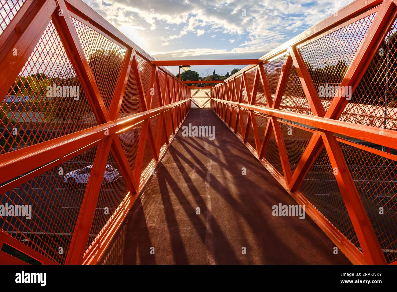 For pedestrian safety, a fenced-in metal walkway crosses over a road ...