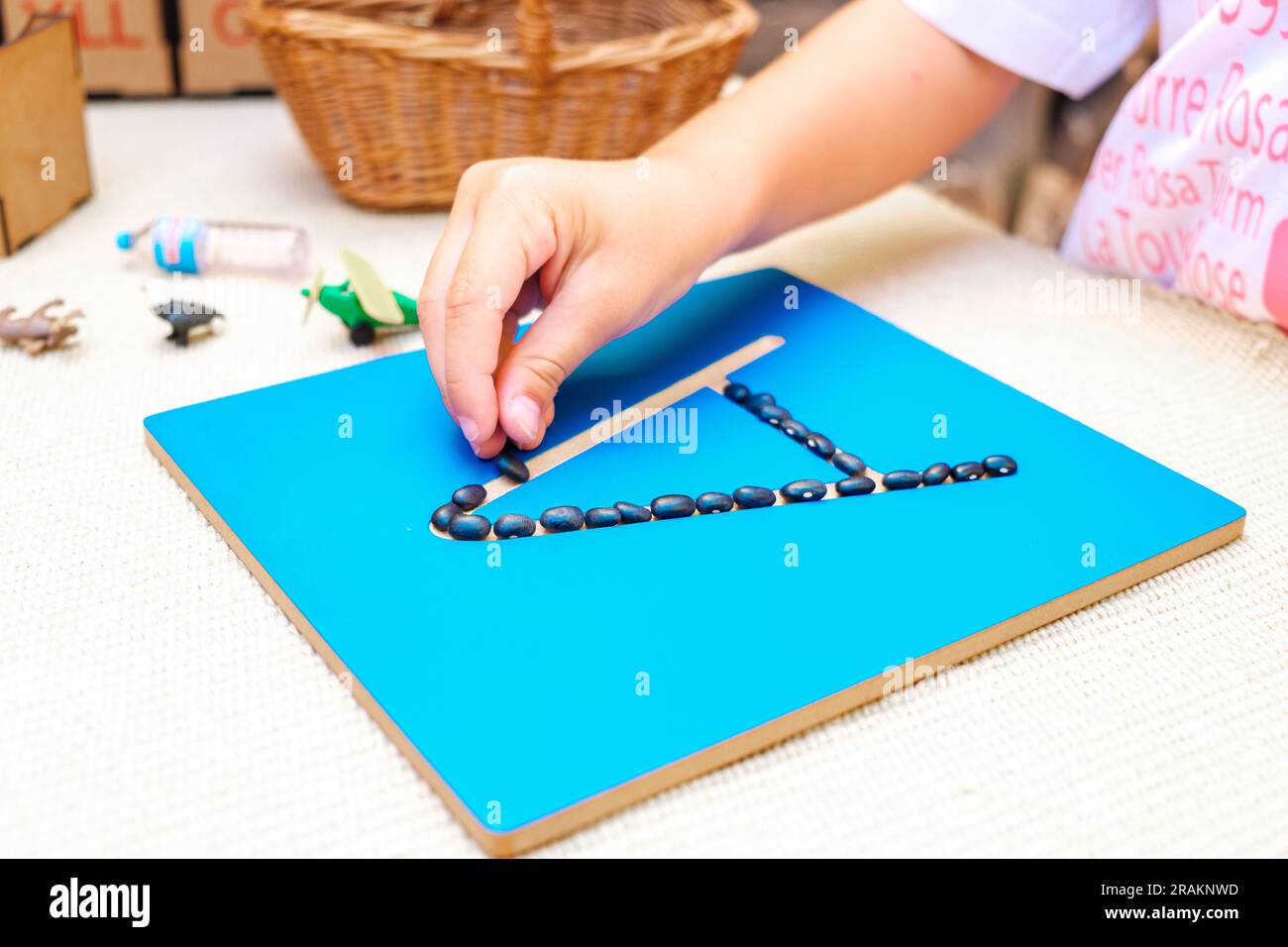A girl tracing the outline of a letter, using the montessori ...