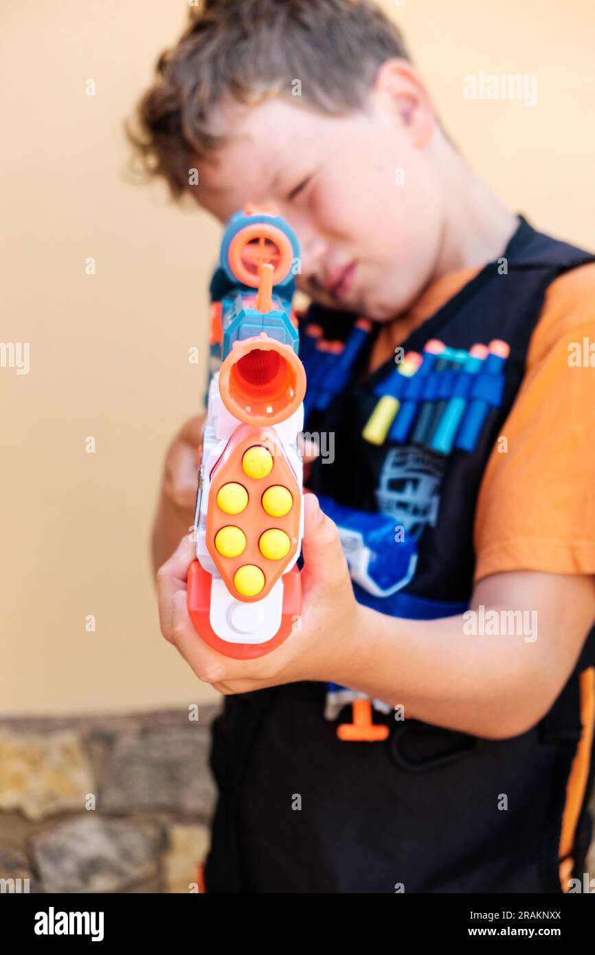 A young marksman takes aim with an air pressure gun, focused on hitting ...
