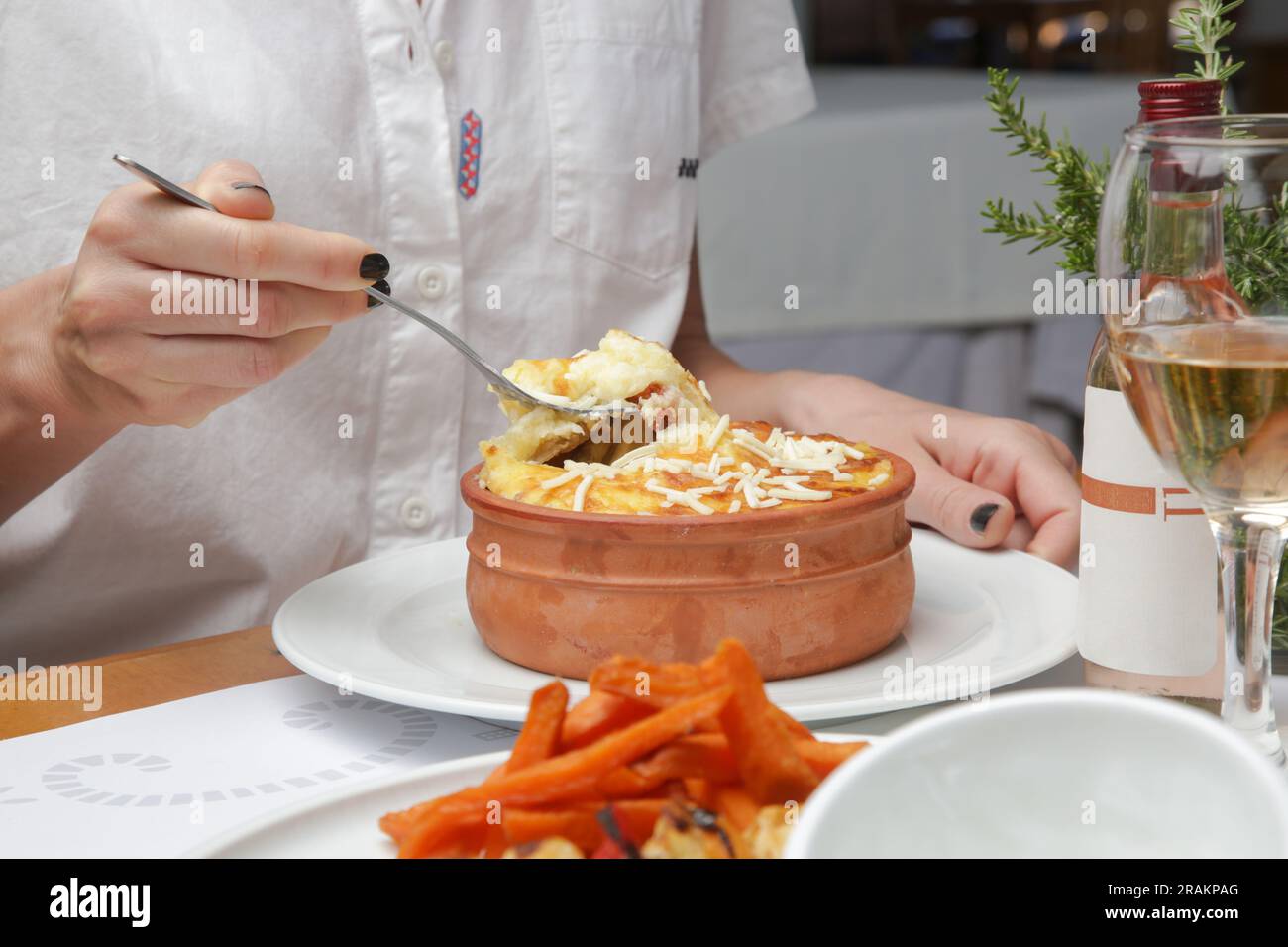 Woman eating traditional greek moussaka prepared in clay pot Stock ...