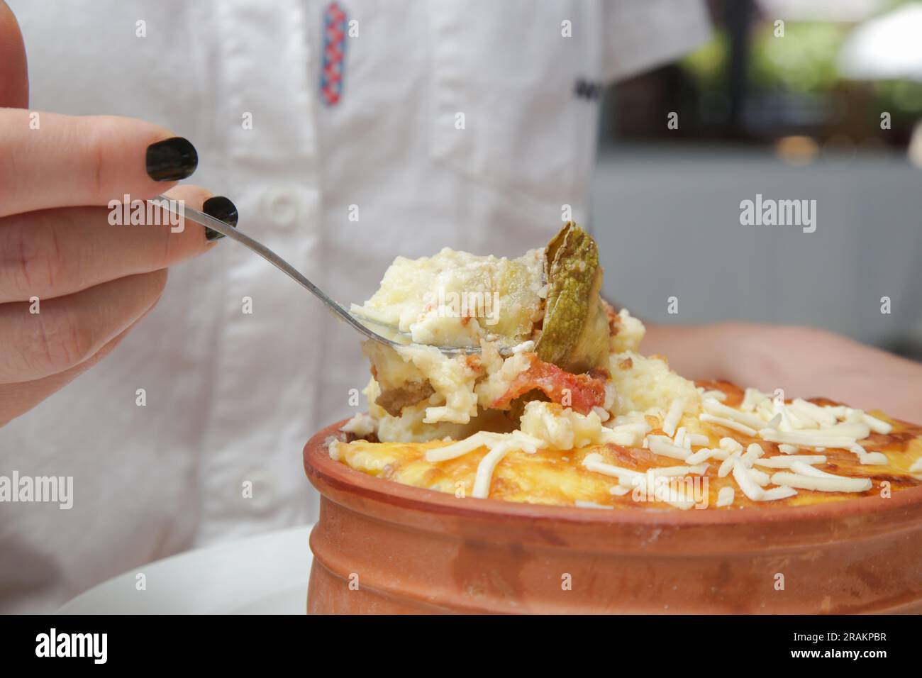 Woman eating traditional greek moussaka prepared in clay pot Stock ...