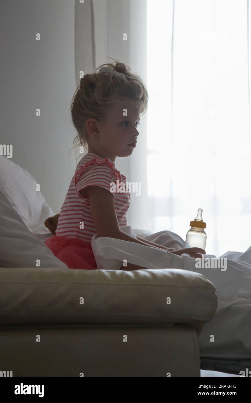 Cute little girl in bed holding plastic baby bottle, concept of ...