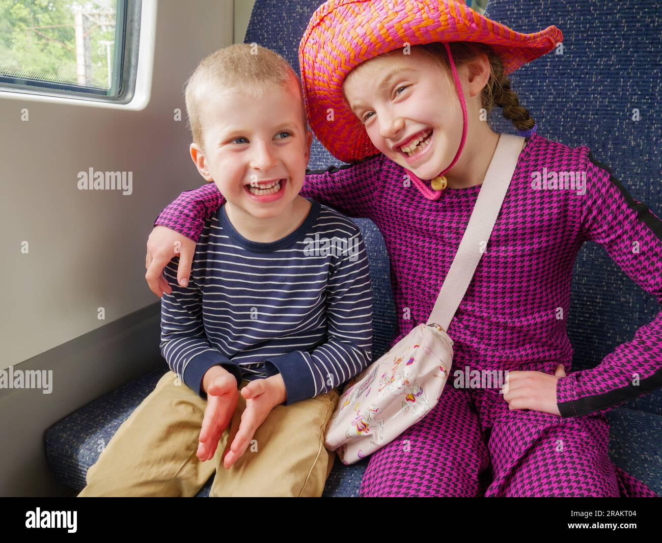 Happy smiling children who are brother and sister travelling by train ...