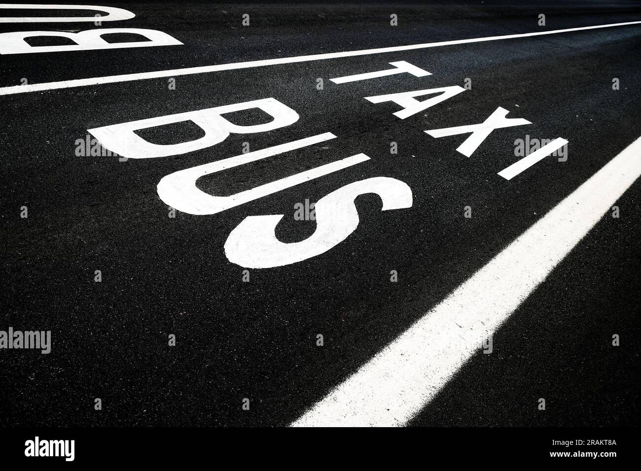 Bus lane with taxi road signage, white reflective paint on black road ...