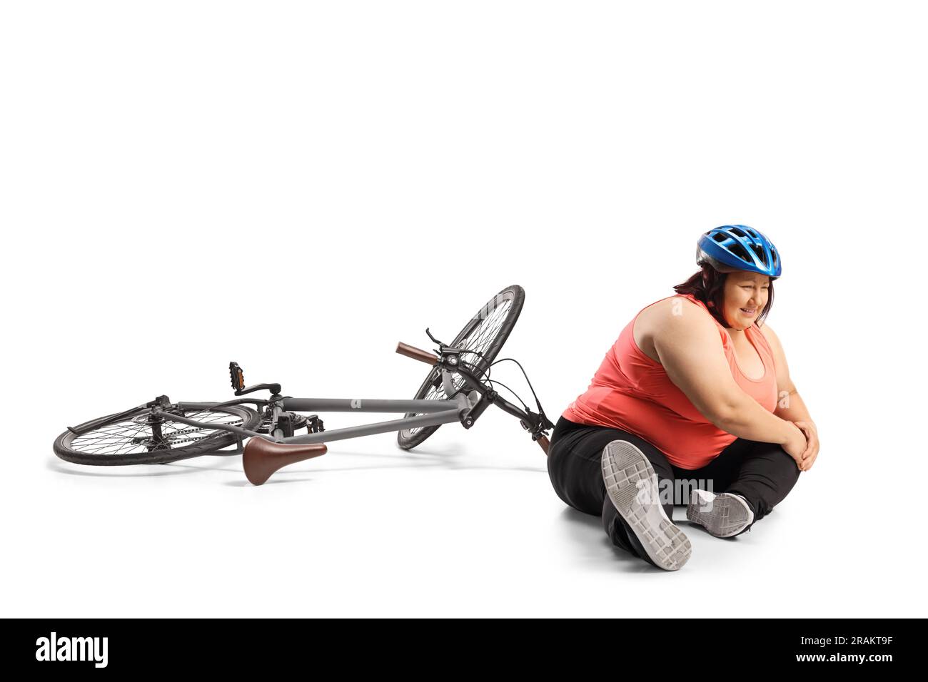Female bicycle rider sitting on the ground and holding an injured knee ...
