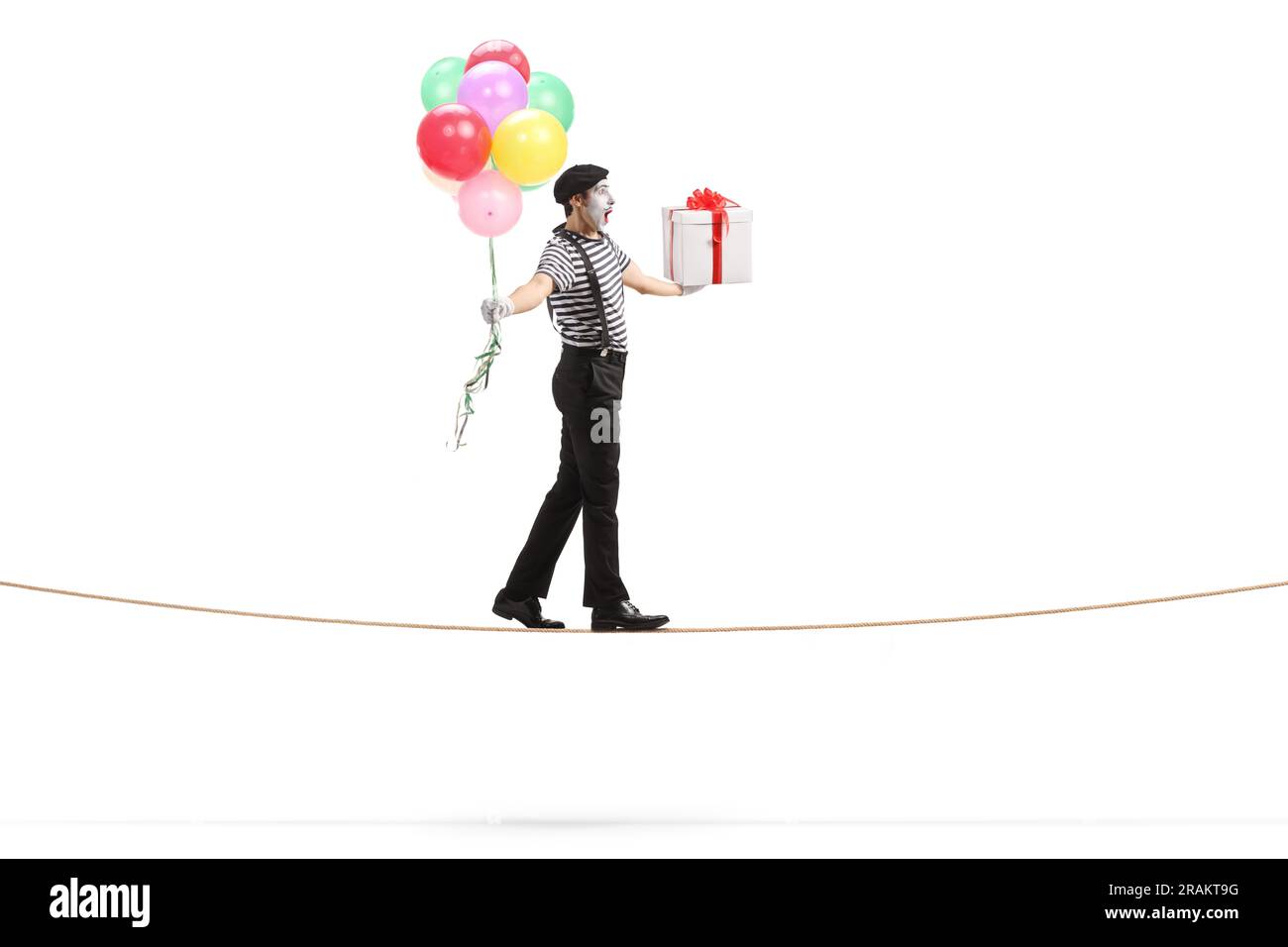 Full length profile shot of a mime walking on a rope and carrying ...