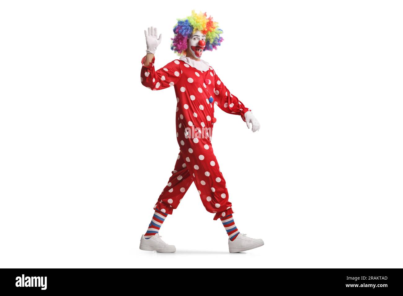 Full length shot of a clown in red costume walking and waving isolated ...