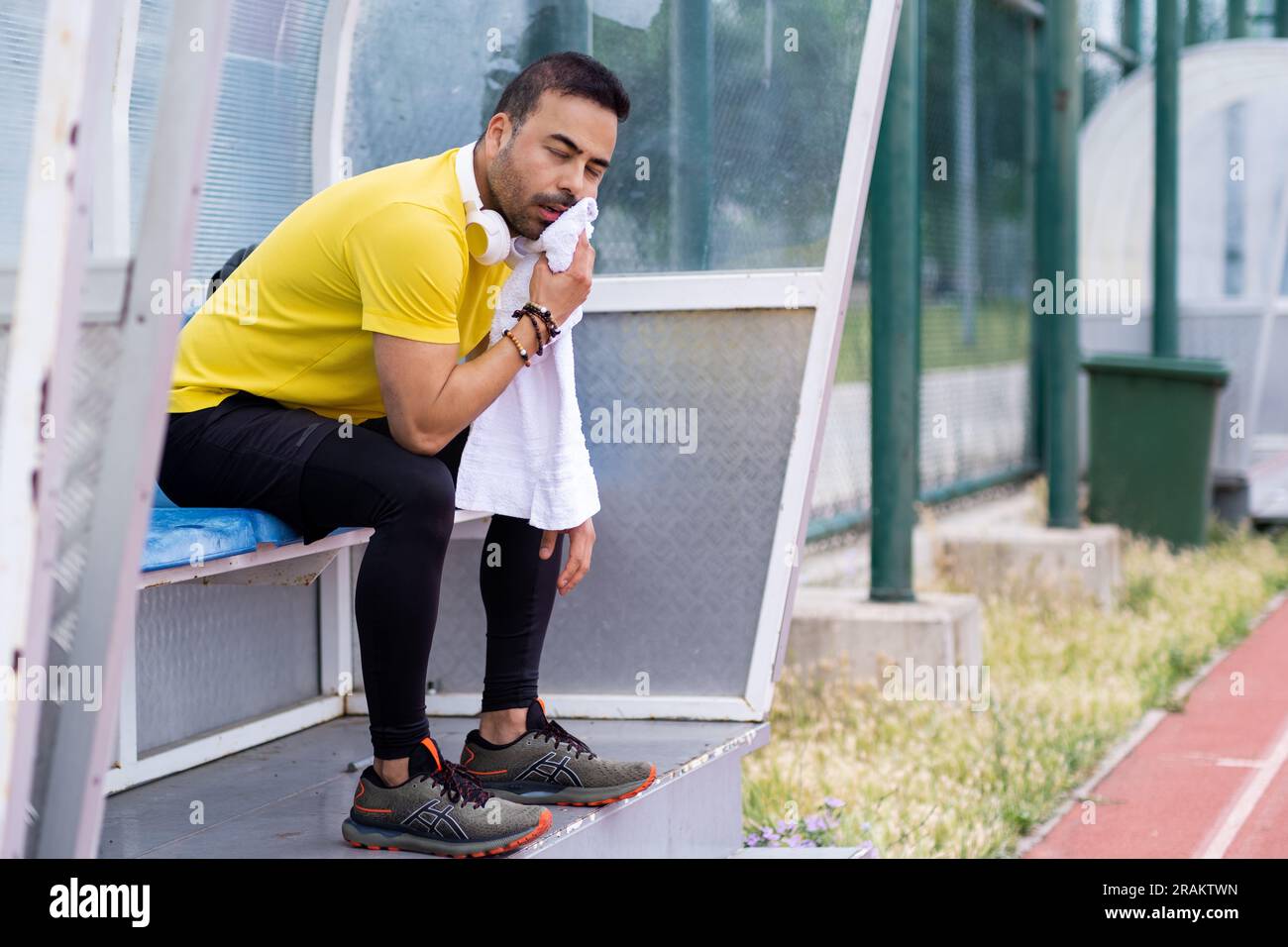 Fatigued man wiping sweat from face with clean towel sitting on chair ...