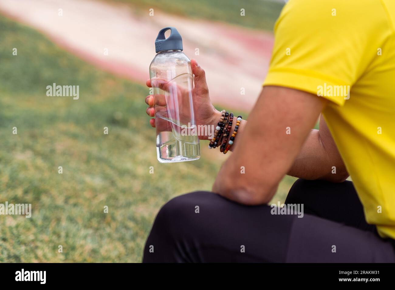 The athlete, taking a break, rests at the sports arena, holding his ...
