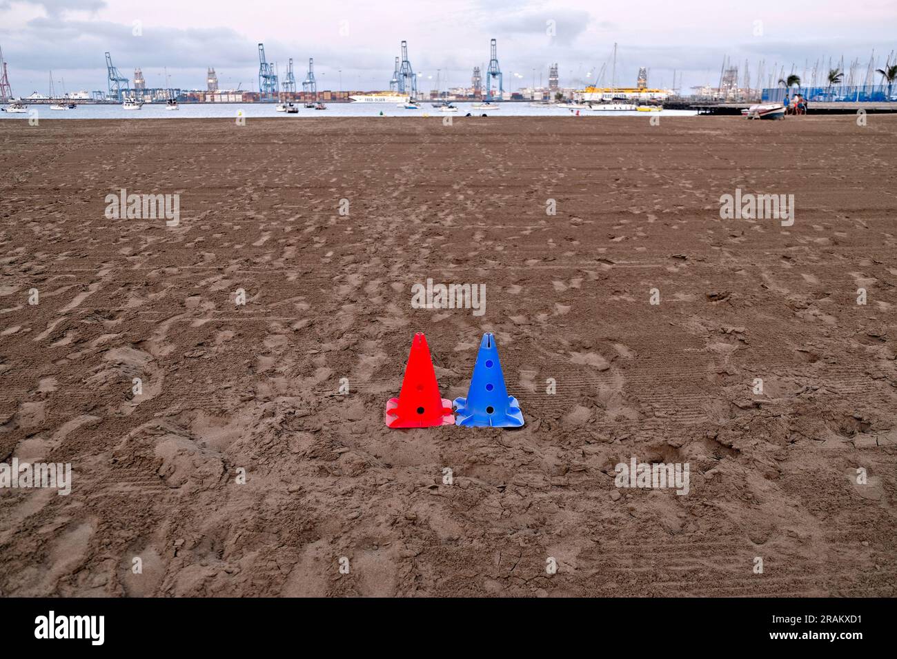 Colors red and blue, two plastic cones on an empty beach in evening ...