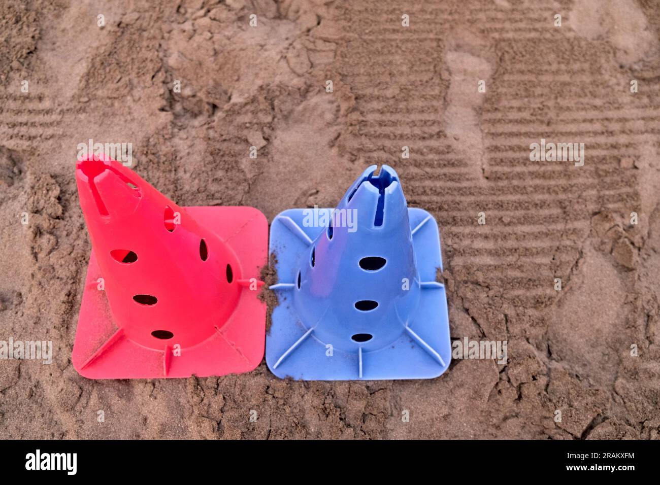 Red and blue plastic cones on a sand surface, close top view Stock ...