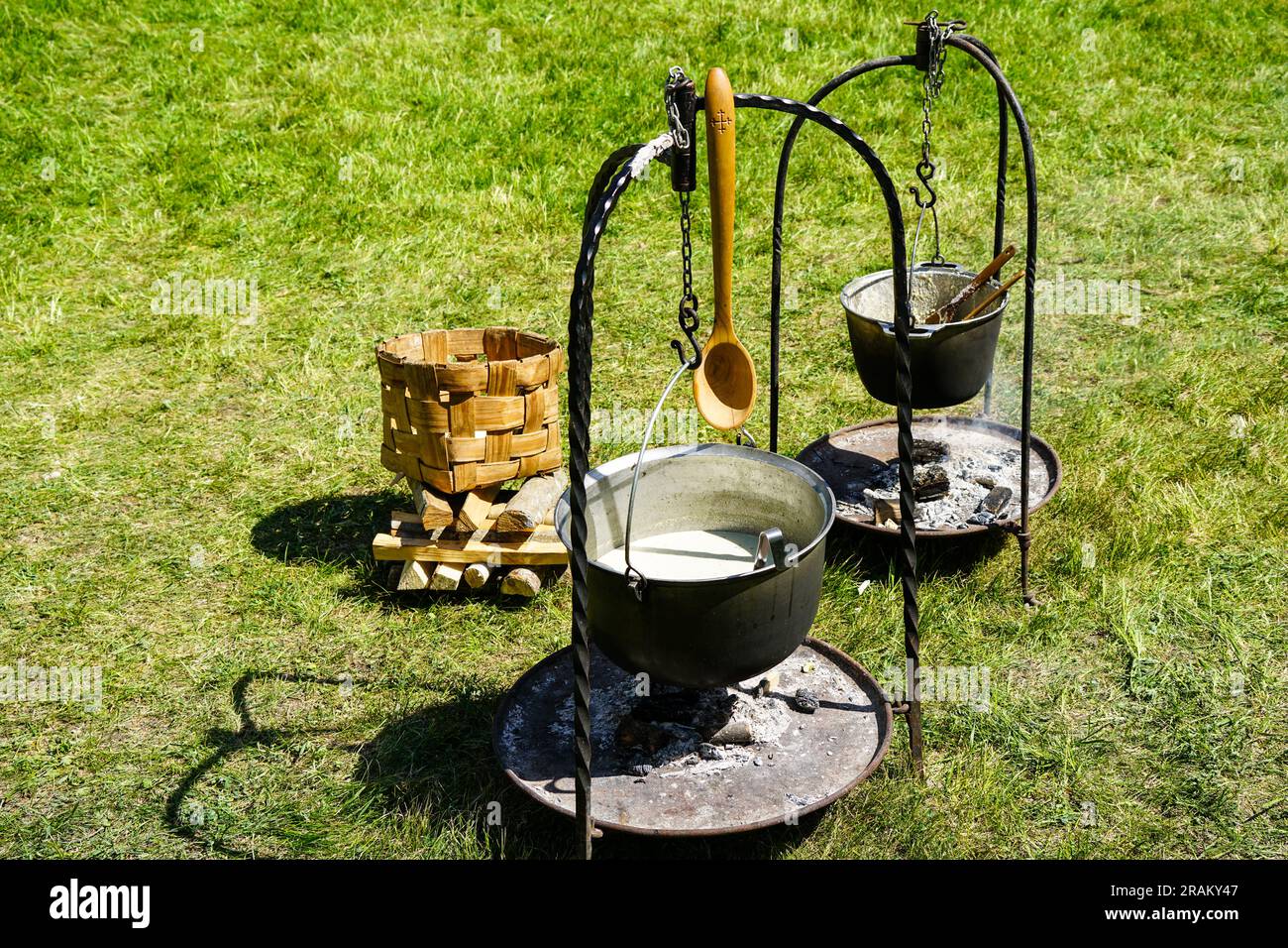 Cooking on a fire in a green meadow using a metal stand with a hanging ...