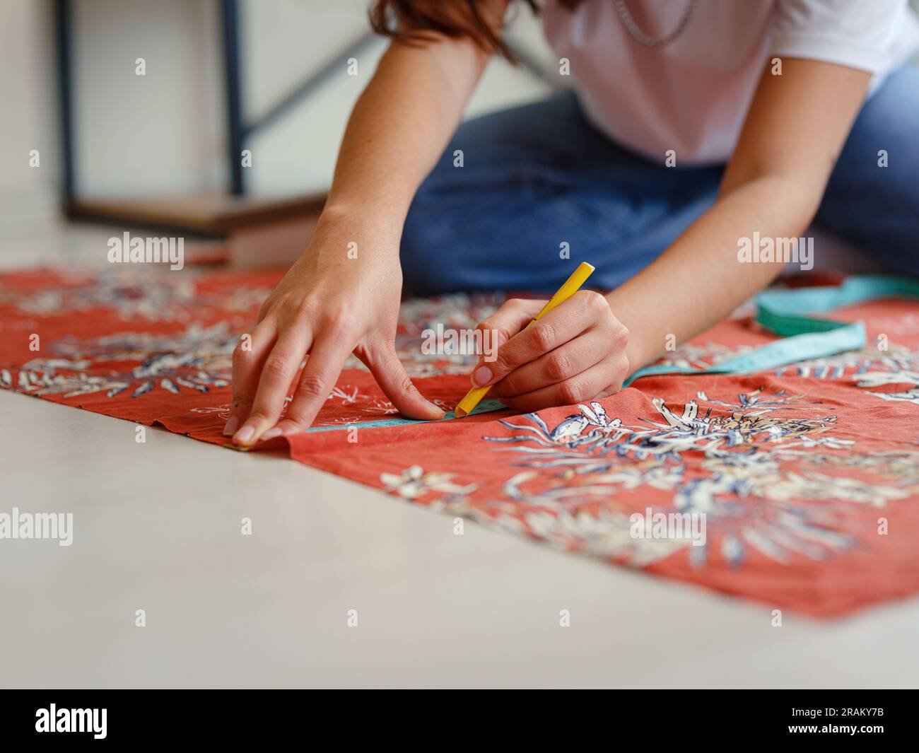 Concentrated young woman tailor cuts with scissors pattern dress detail ...