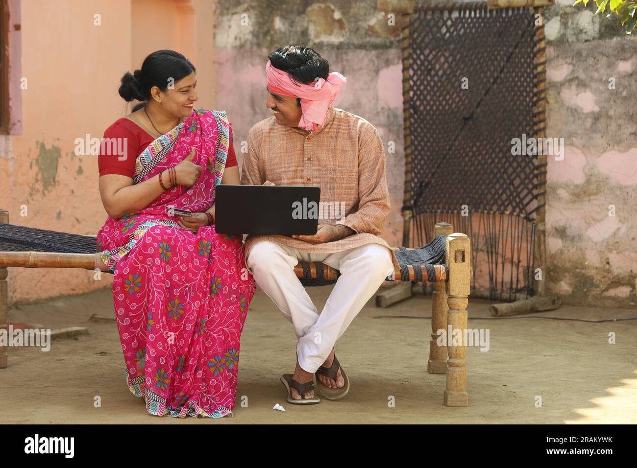 Happy Indian village family using the laptop sitting outside the house ...