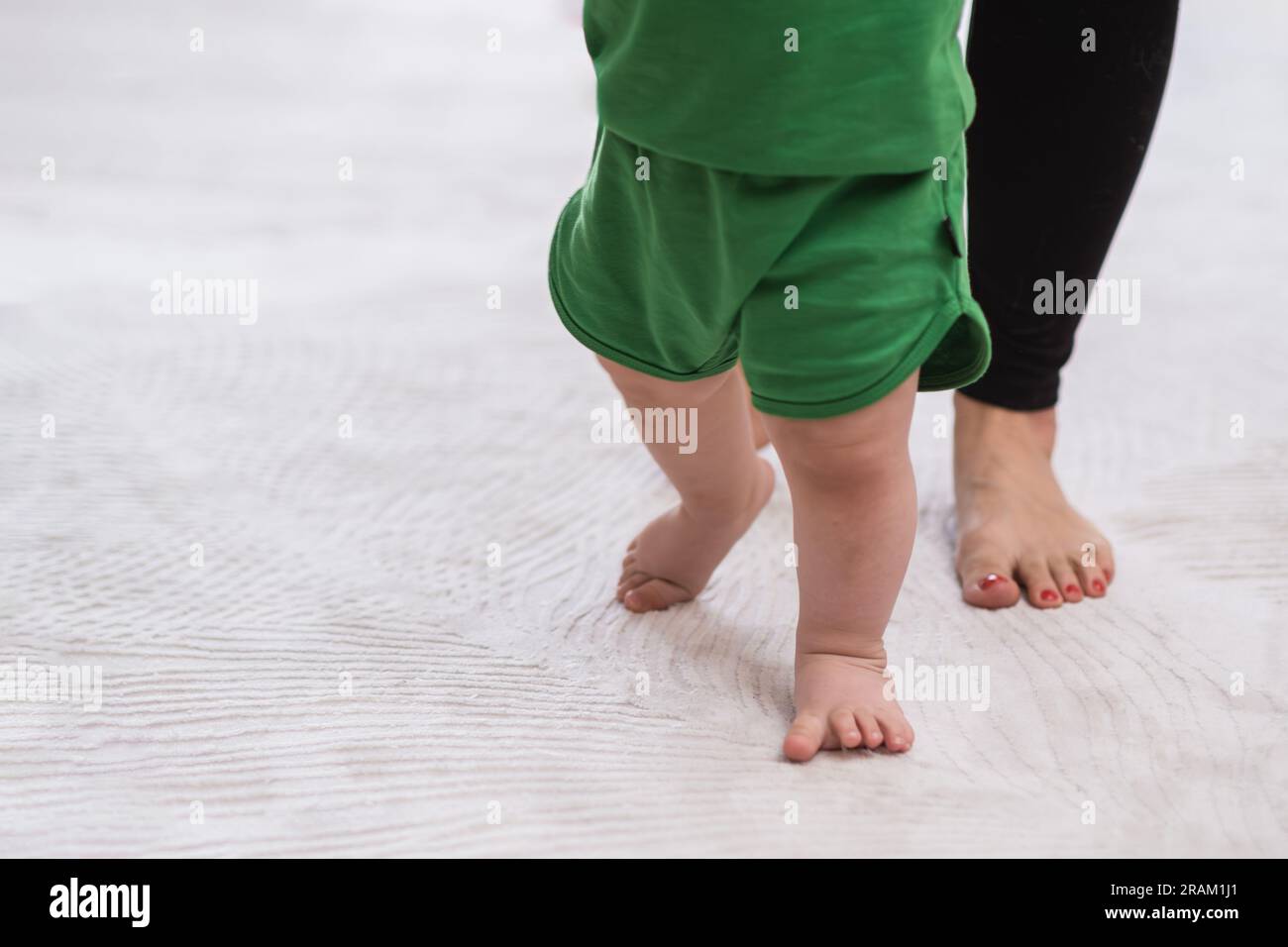 Cute little boy learning to make first steps with little legs on soft ...