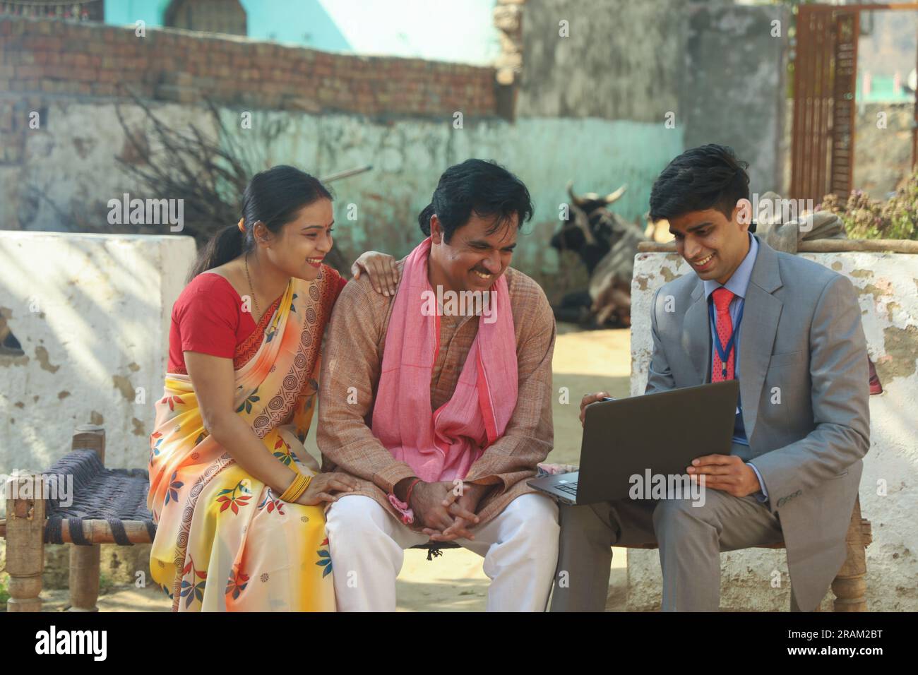 Happy Indian village family sitting with the banker or financial consultant using the laptop ...