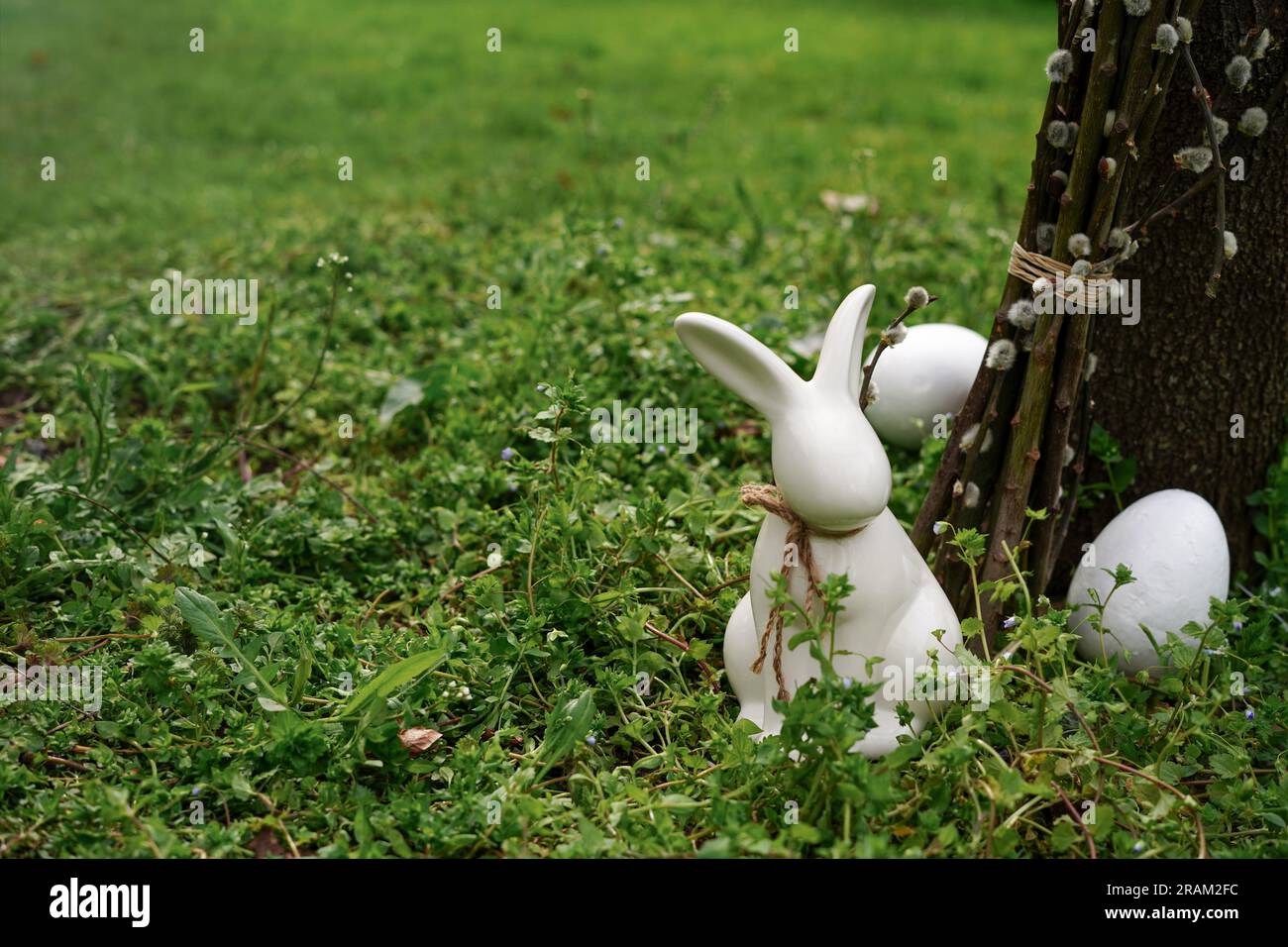 Easter bunny and white eggs with willow branches in the garden on green ...