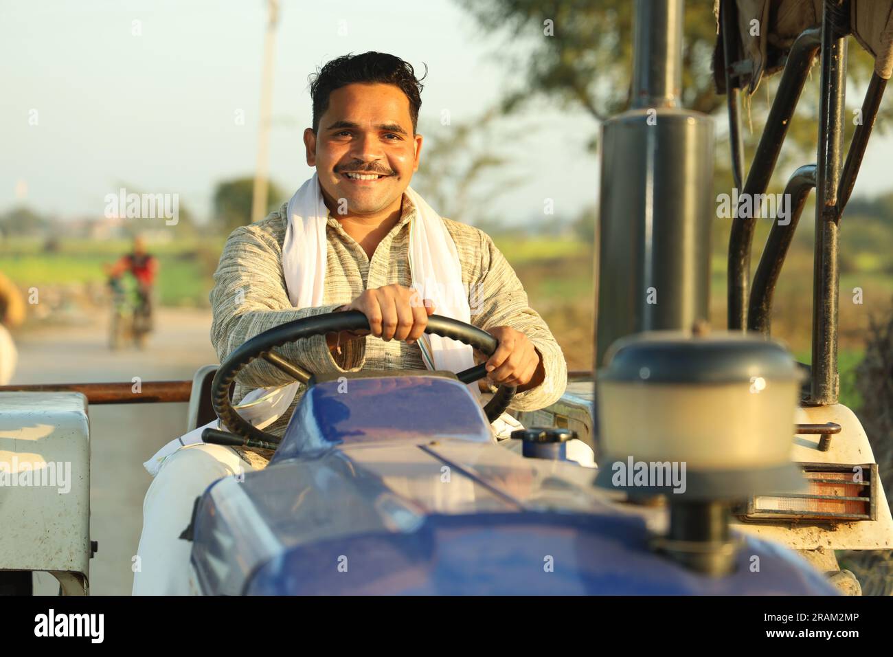 Happy hard working Indian farmer sitting on a tractor in a day time ...
