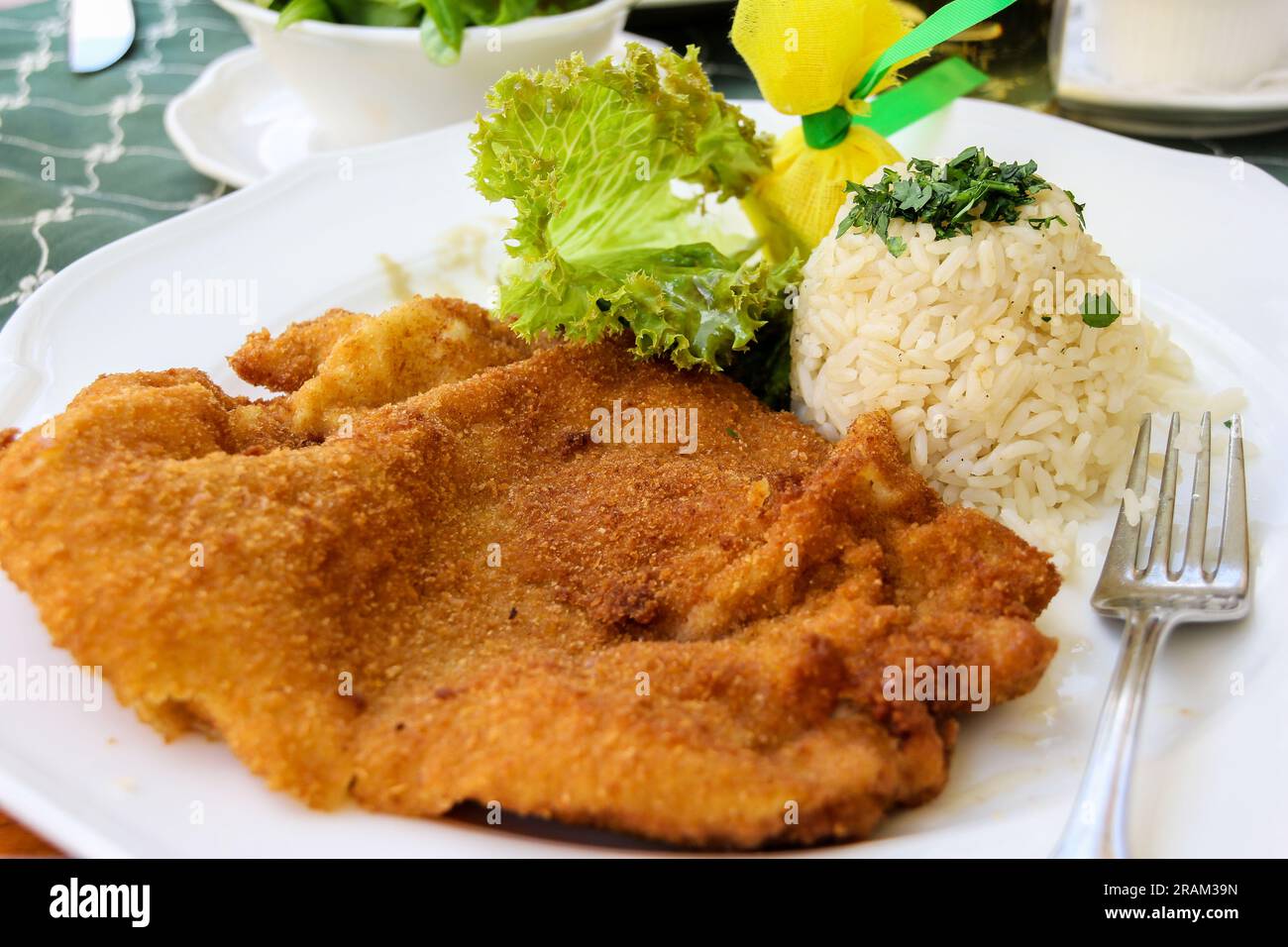 Viennese Schnitzel with rice as side dish and lemon and salat leaf as ...