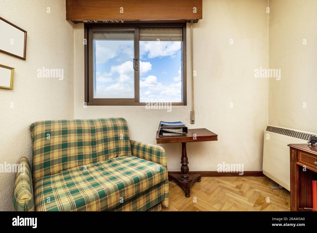 Small living room with checkered fabric upholstered sofa bed and wooden ...