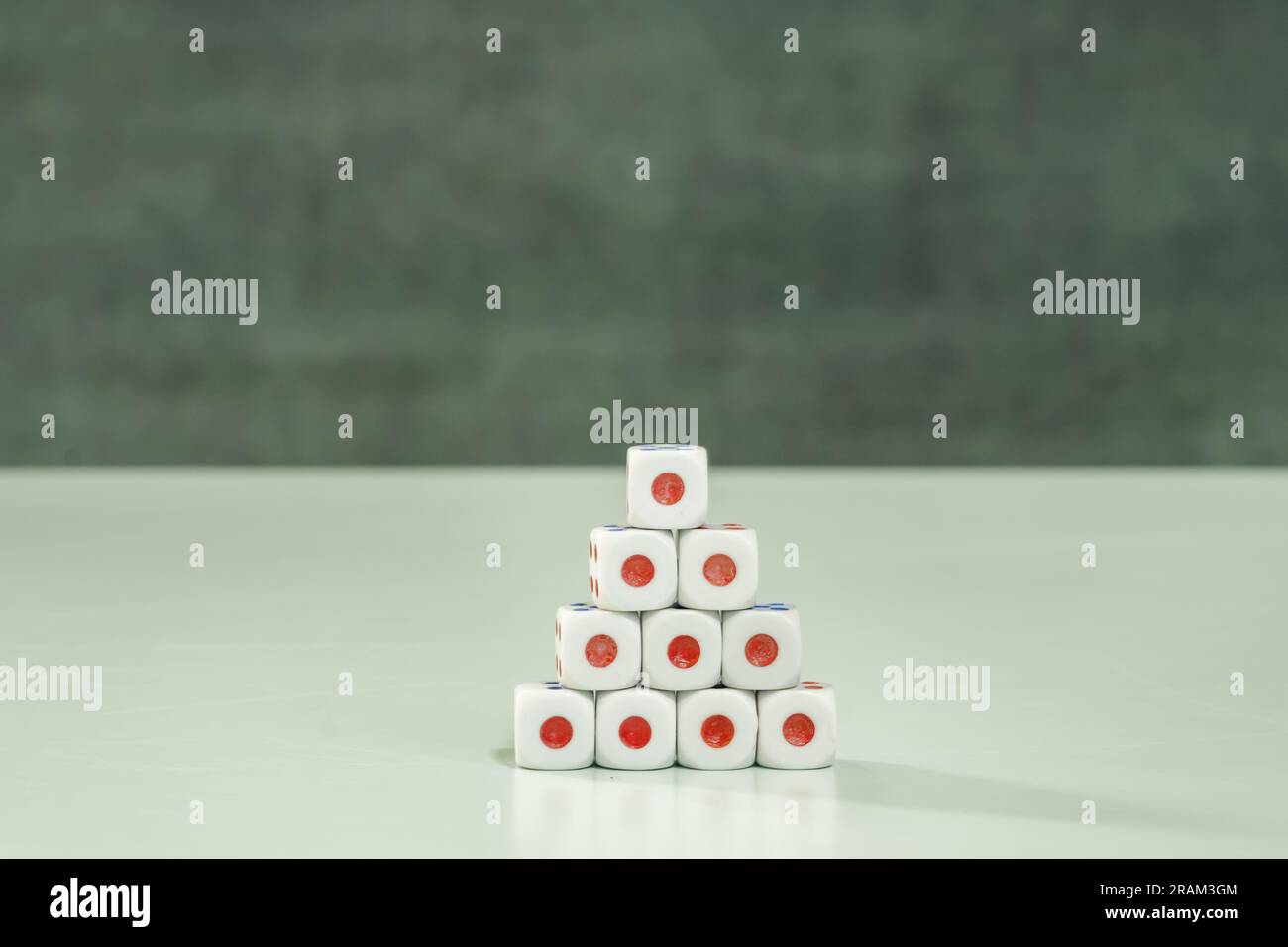 Some gambling dice placed in a pyramid shape on a smooth blue surface ...
