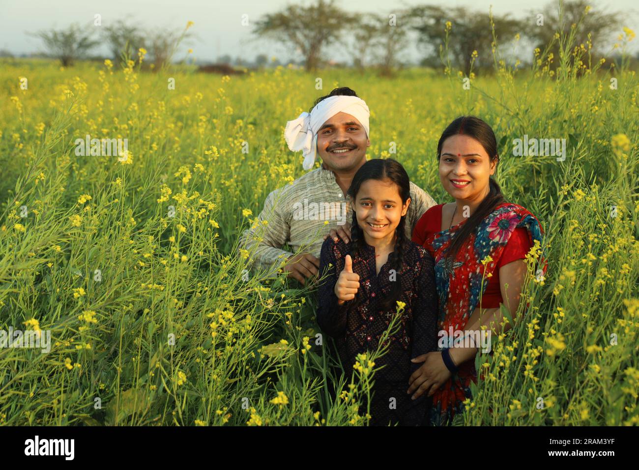 Happy Indian farmers family standing in mustard field in day time ...