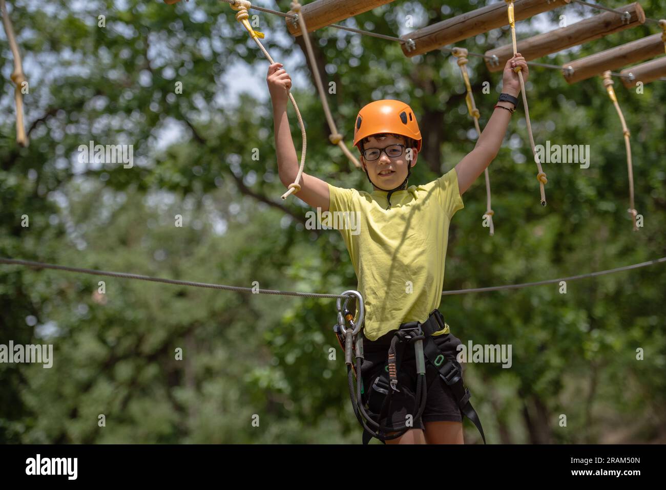 Boy enjoys climbing in the ropes course adventure. Happy boys playing ...