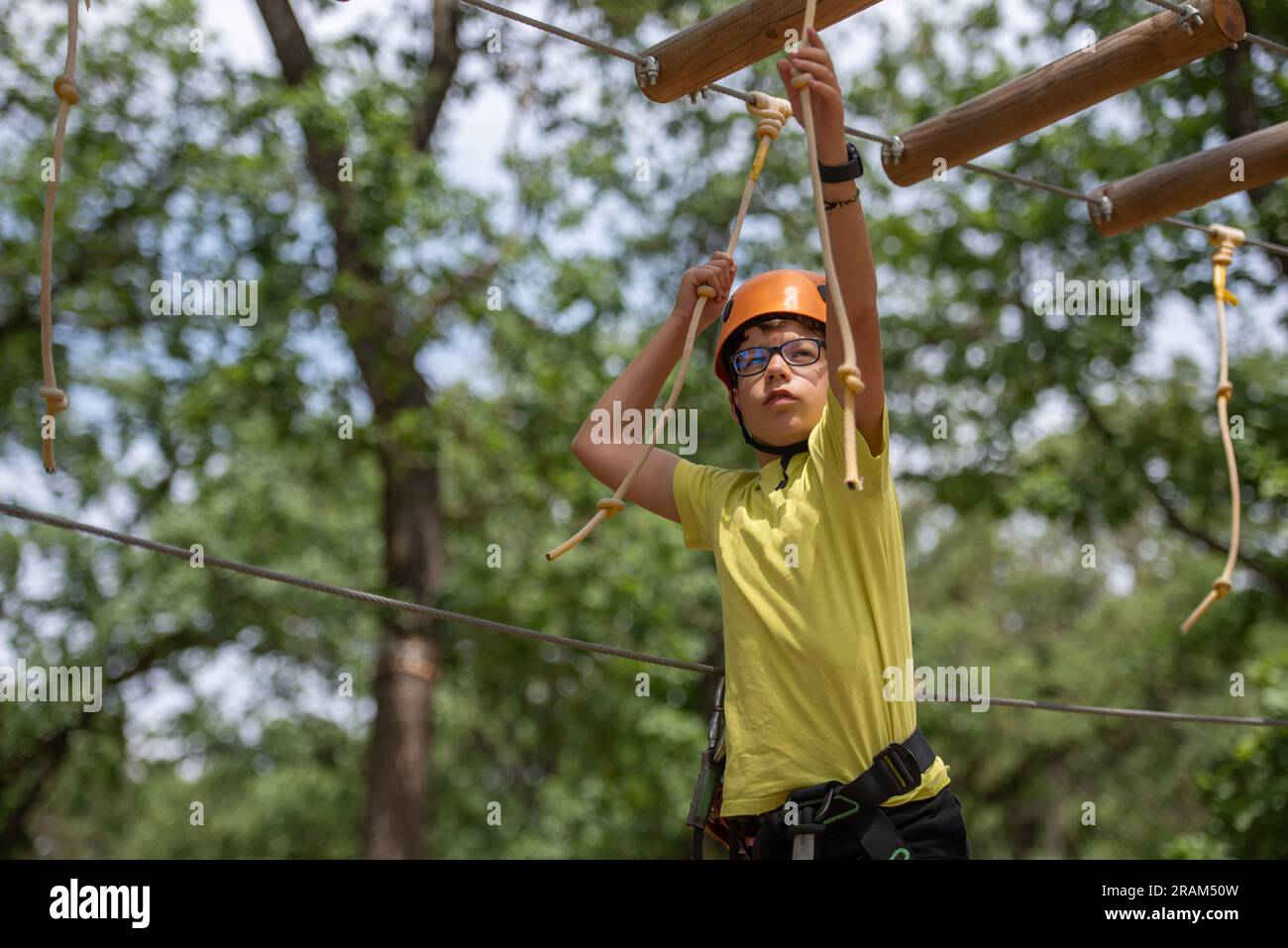 Boy enjoys climbing in the ropes course adventure. Happy boys playing ...