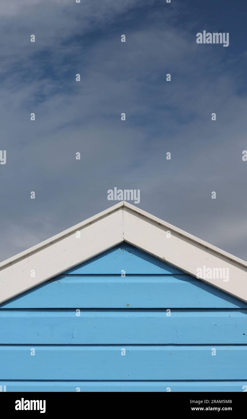 Old English beach hut with pitched roof in blue and white against sky ...
