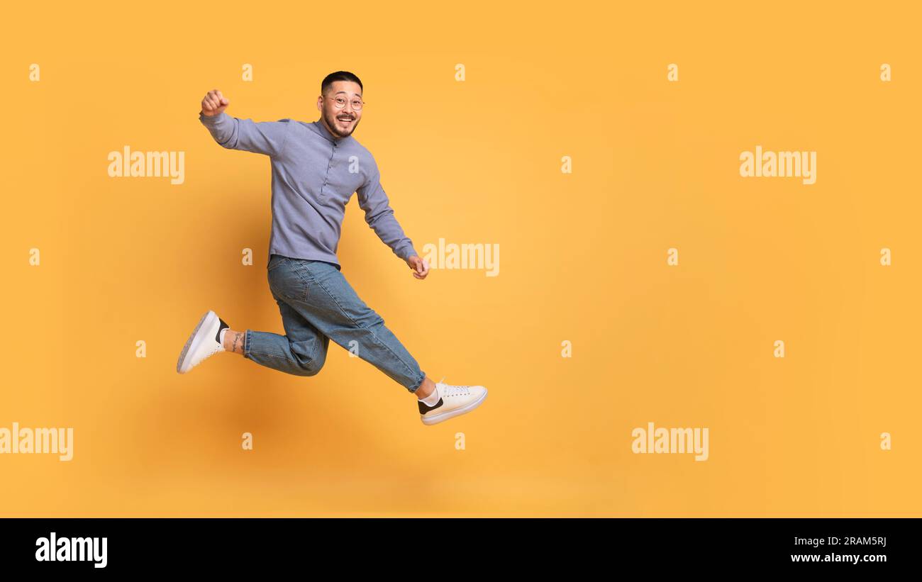 Hooray. Overjoyed Young Asian Guy Jumping In Air Over Yellow Background ...