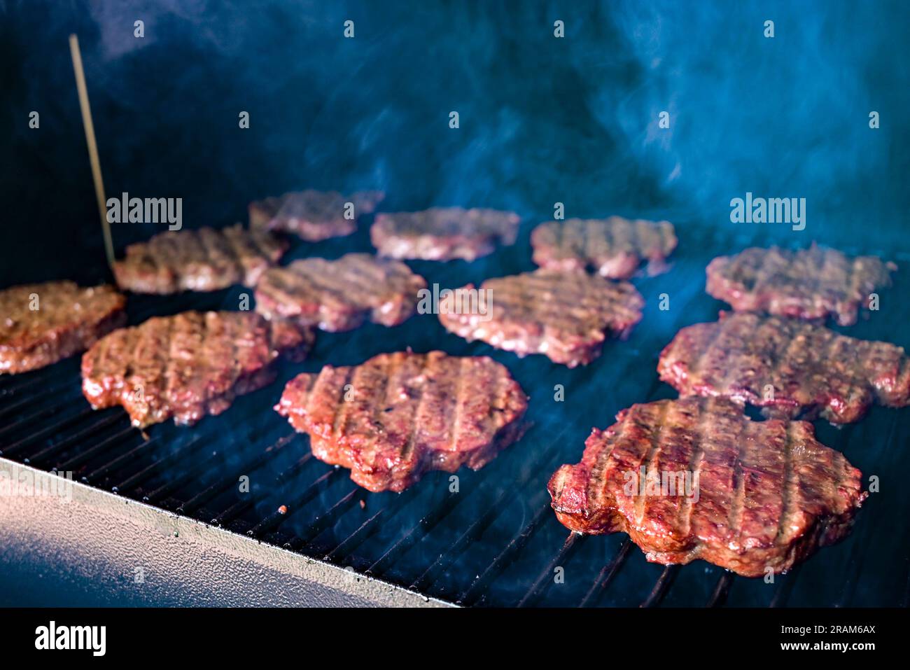 Burger patties on top of the grill being cooked, with smoke in the back ...