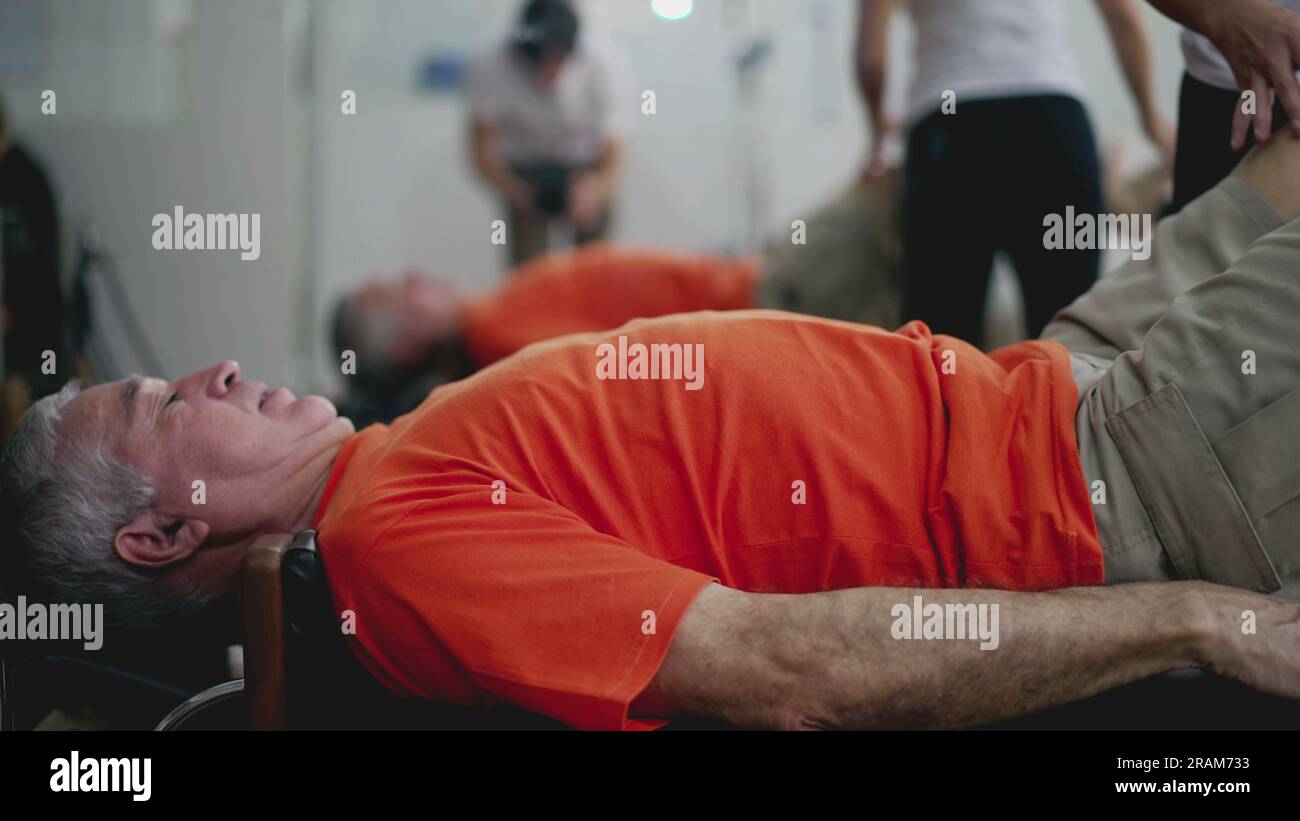 Physical therapist helping senior man to use Pilates machine, old age ...