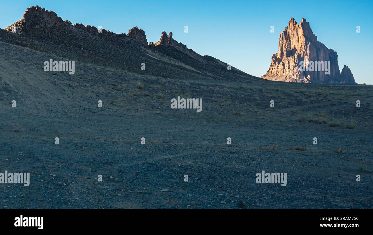 Shiprock (rock formation) sunlit in evening with clear, blue sky ...