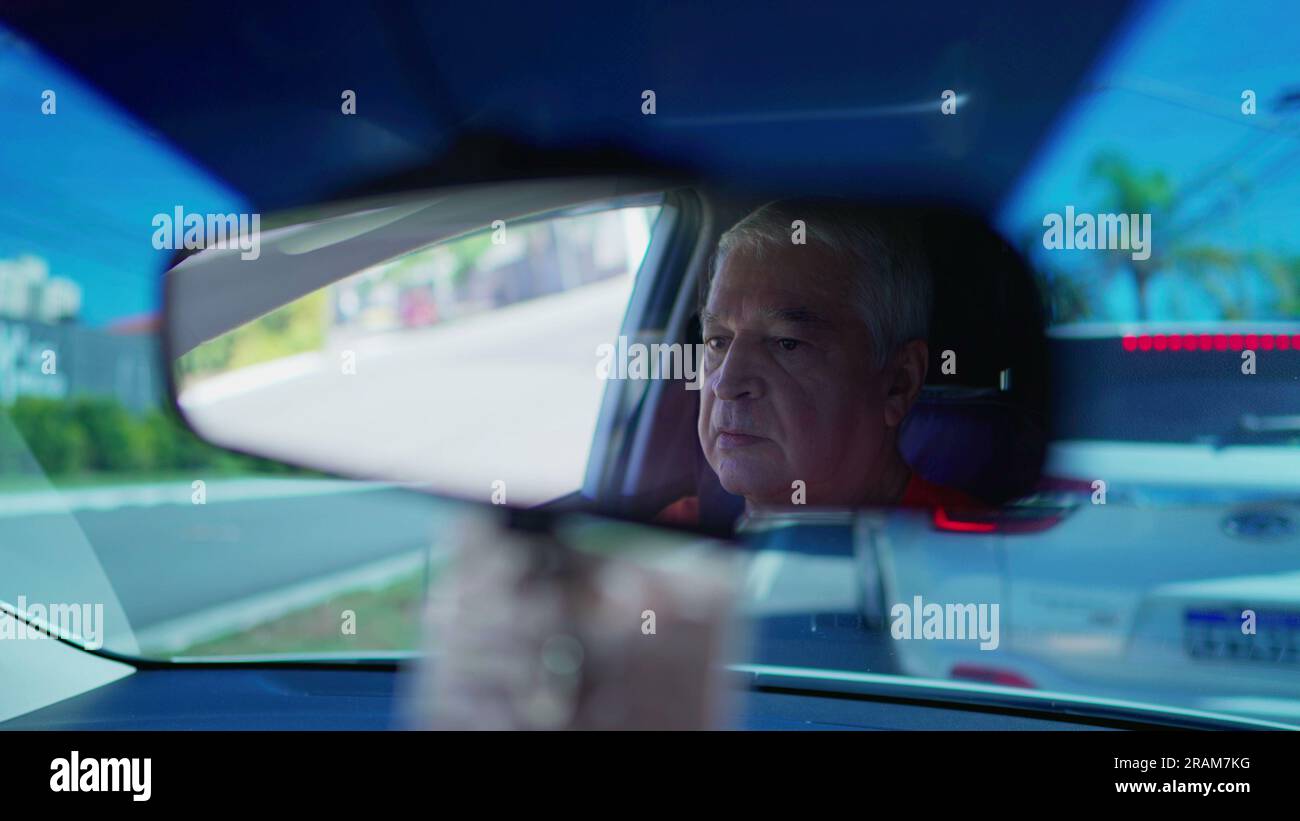 Senior driver stuck in traffic seen through rearview mirror reflection ...