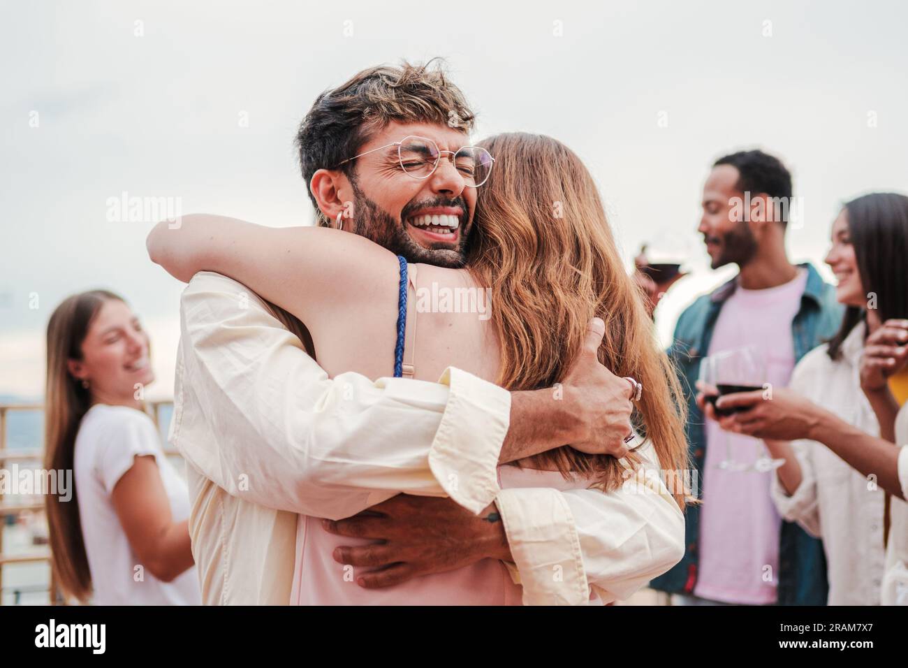 Happy man and excited woman hugging at a party with a group of people ...